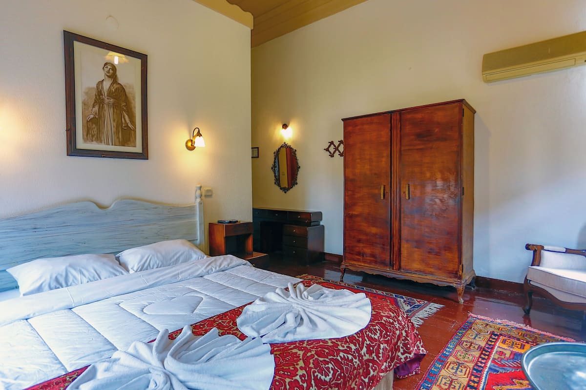 Quarto com cama, guarda-roupa de madeira, escrivaninha e uma cadeira.