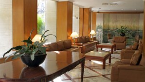 Um hall amplo com uma grande mesa de centro de madeira, sofás de couro e uma planta em vaso.