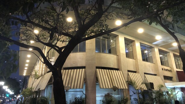 Um edifício moderno com grandes janelas e uma árvore na frente.