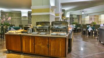 Uma mesa de buffet com várias estações de serviço, um balcão de madeira e uma variedade de alimentos.