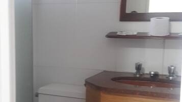 Casa de banho com sanita, lavatório e espelho.