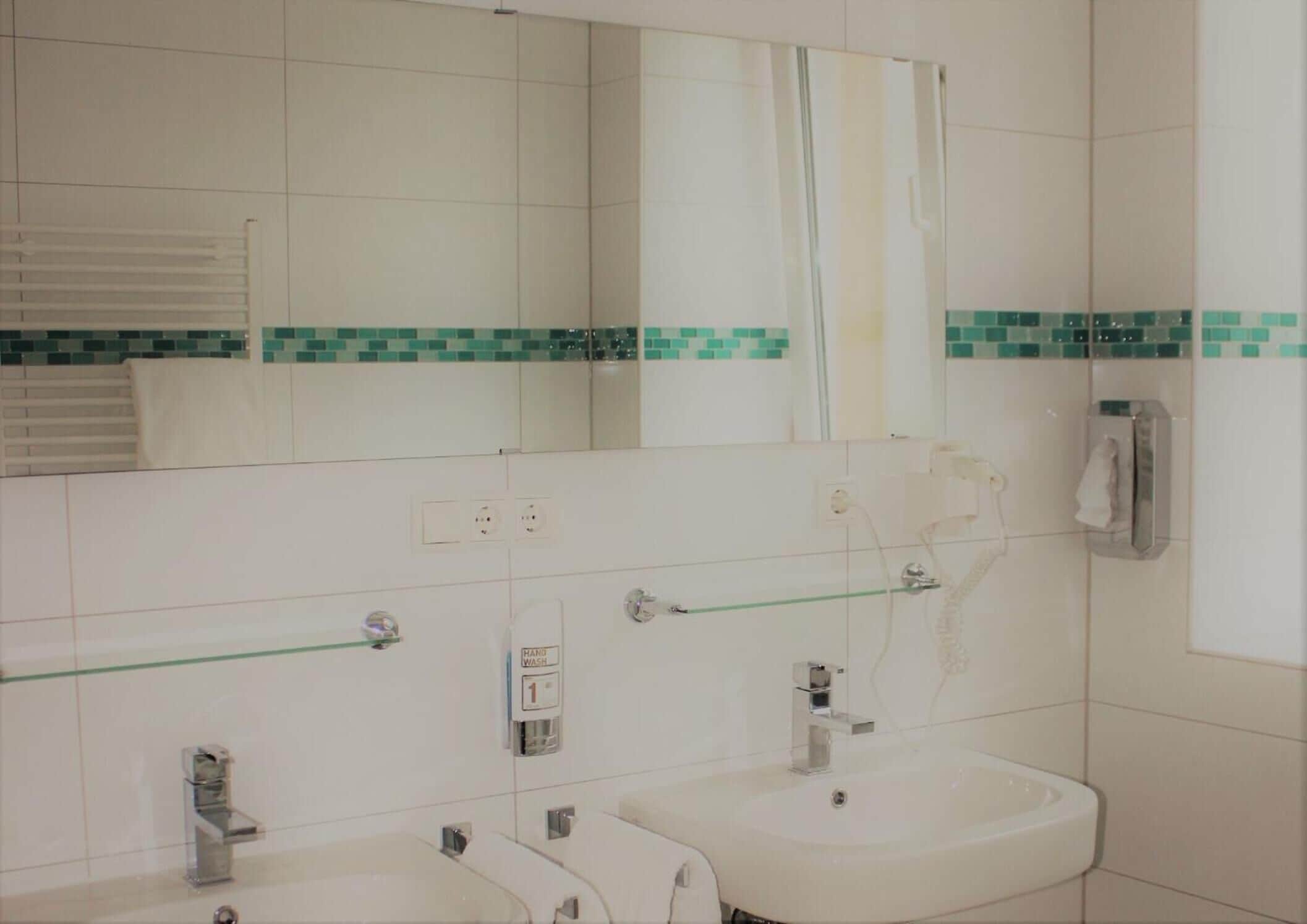 Casa de banho com duas pias, um espelho e cabine de duche em vidro.