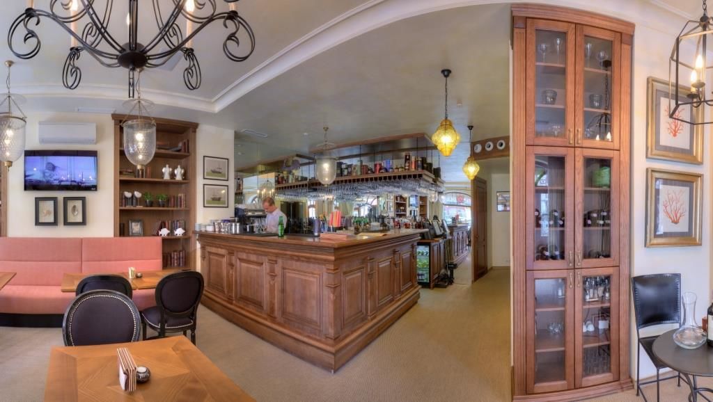 Uma sala de estar espaçosa com um balcão de madeira, um sofá rosa e uma mesa de jantar.