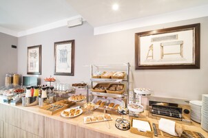 Um balcão de buffet com diversos alimentos, uma máquina de café e quadros nas paredes.