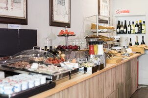 Uma área de buffet com diversos alimentos, seleção de vinhos e placa indicando proibição de fumar.