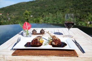 Uma mesa de jantar com um prato de comida, um copo de vinho tinto e garfo e faca.