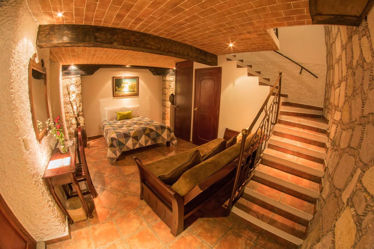 Um quarto com cama, escrivaninha, cadeira, janela e escada.