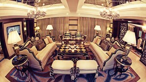 Uma sala de estar luxuosa com uma mesa de centro xadrez, sofás confortáveis e lustres elegantes.