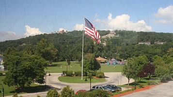 Um mastro com a bandeira americana, um estacionamento e uma área verde com árvores e um parquinho.