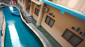 Piscina estreita com um barco, rodeada por edifícios com varandas e aparelhos de ar condicionado.