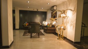 Uma sala de estar moderna com um sofá, poltrona e um abajur de palmeira decorativa.