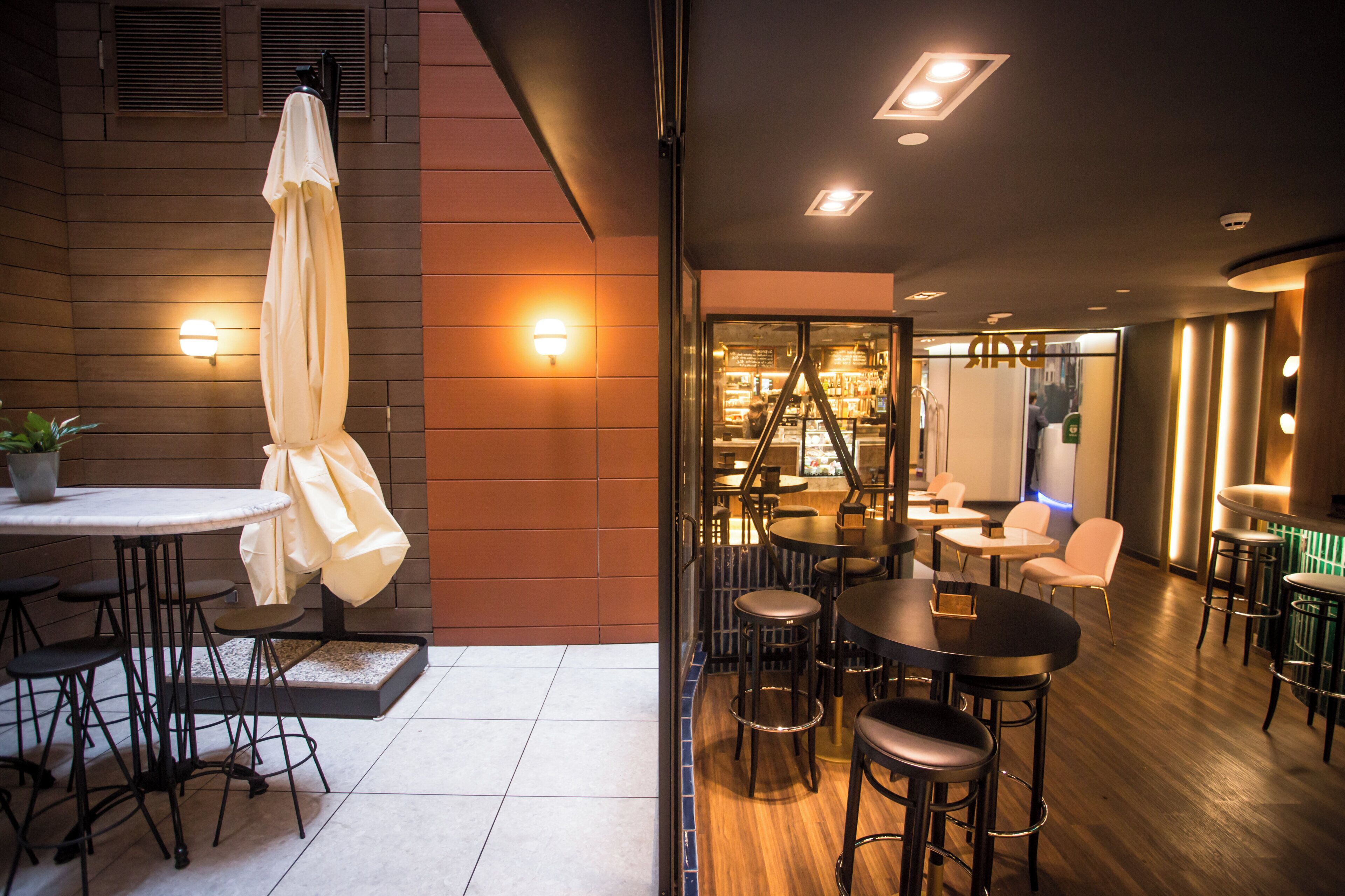 Uma área de bar moderna com banquetas, mesas e balcão.