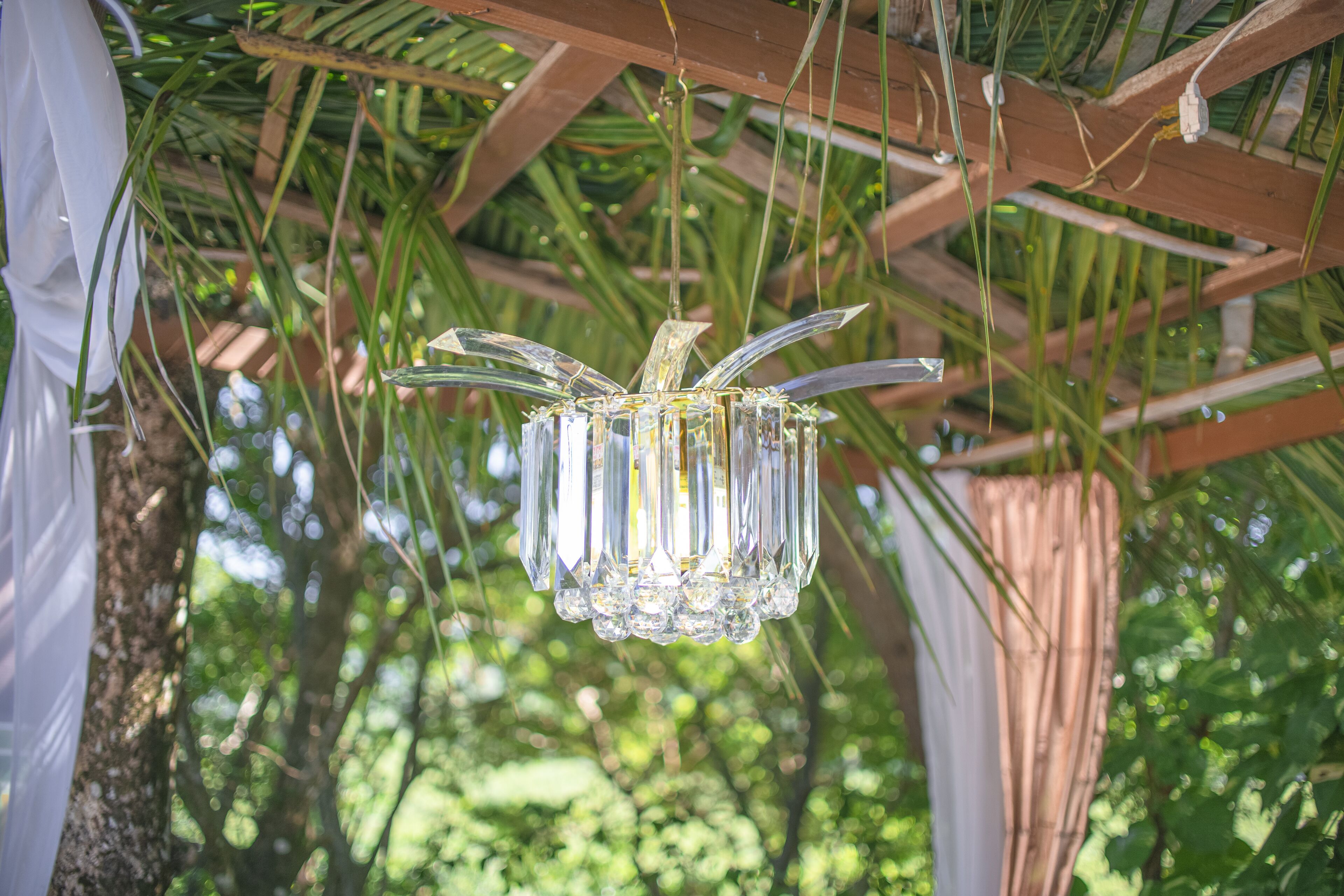 Um lustre de cristal pendurado em uma estrutura de madeira com fundo natural.