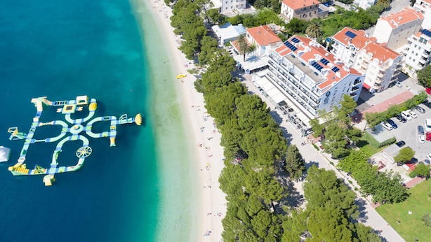 Vista aérea de uma área costeira com praia, edifícios e uma estrutura flutuante peculiar.