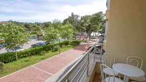 Varanda com vista para um estacionamento, árvores e um edifício ao longe.