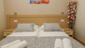 Uma cama de casal com roupa de cama estampada, dois travesseiros e duas toalhas enroladas.