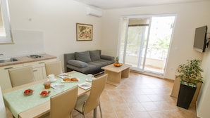 Um espaço compacto com cozinha compacta, área de refeições e varanda com porta deslizante.