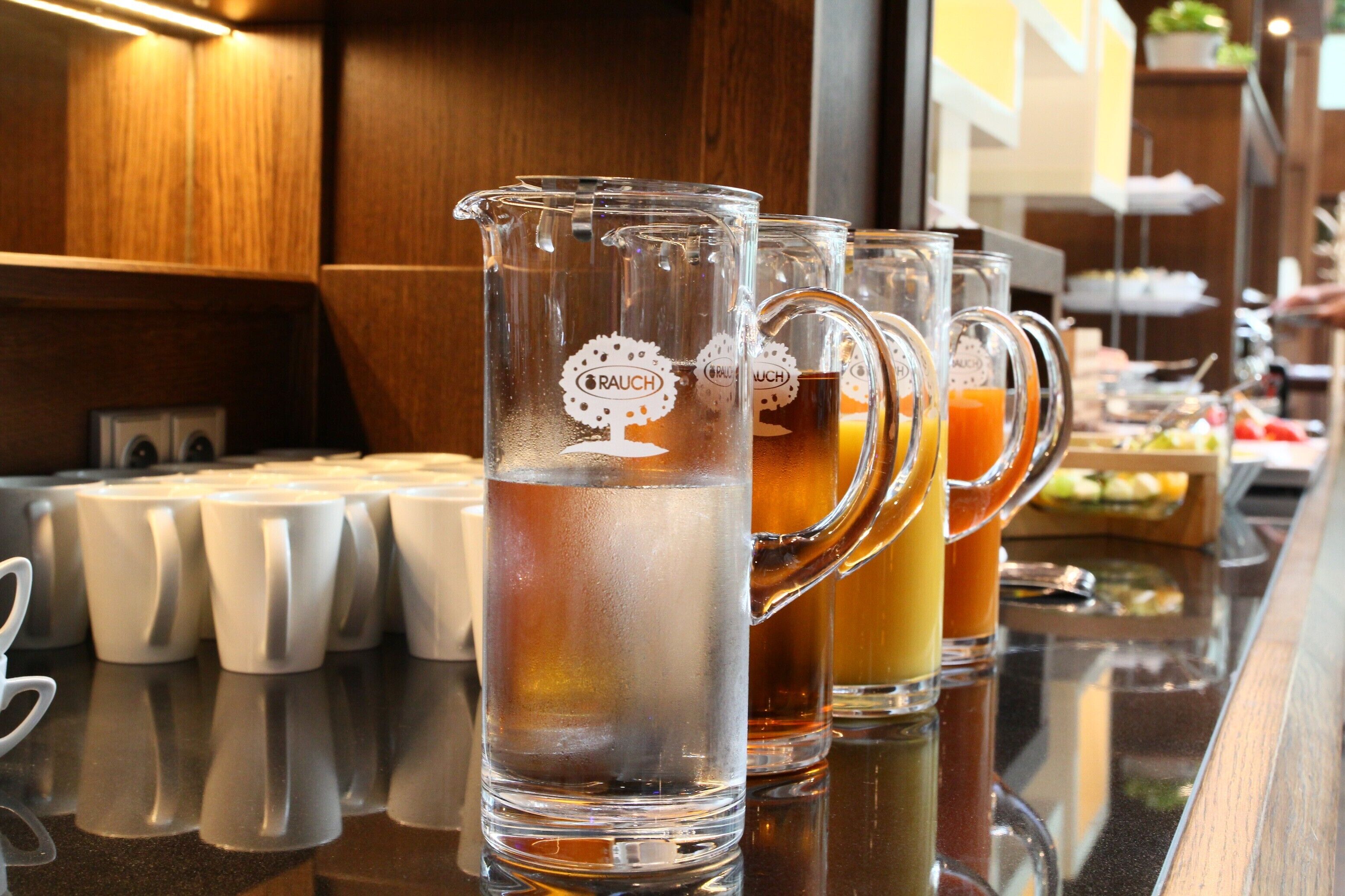 Uma área de bar com vários jarros de bebidas e diversos copos brancos.