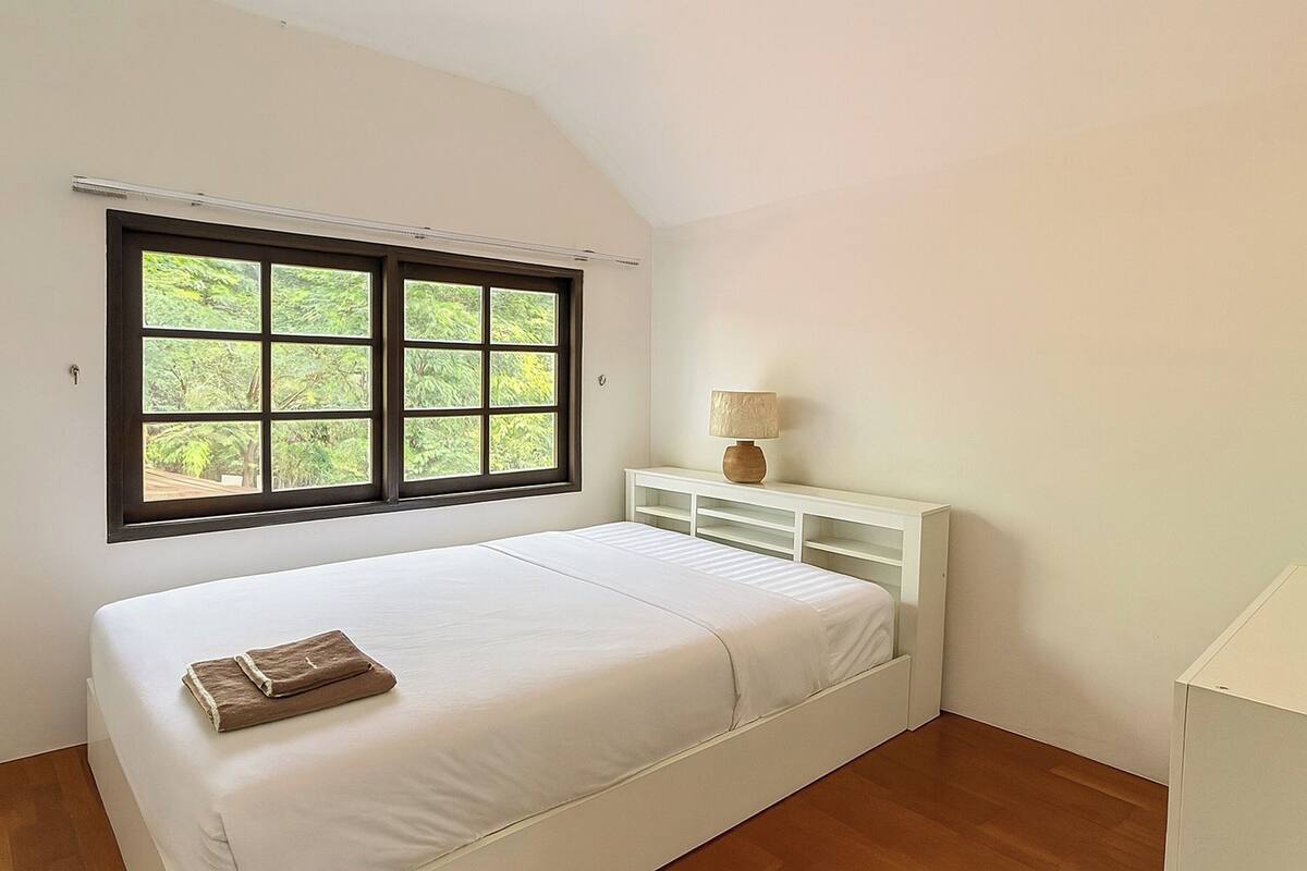 Quarto com cama, janela, mesa de cabeceira e luminária.