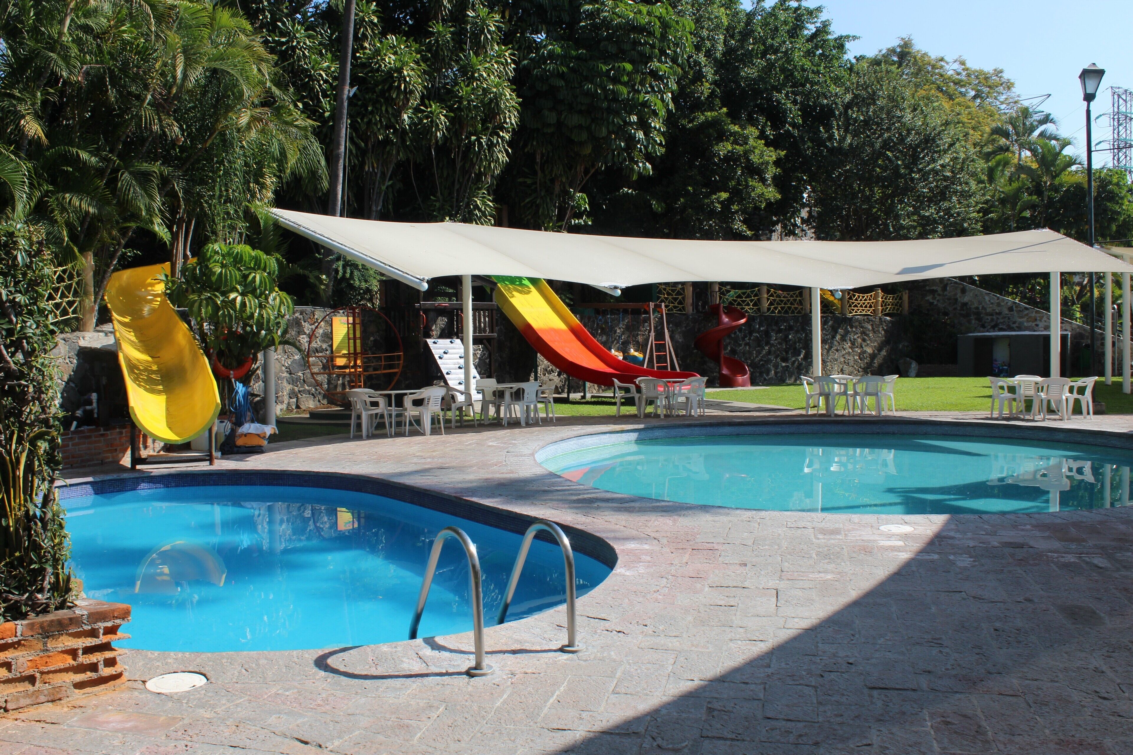 Área de piscina com duas escorregas e zona de estar coberta.