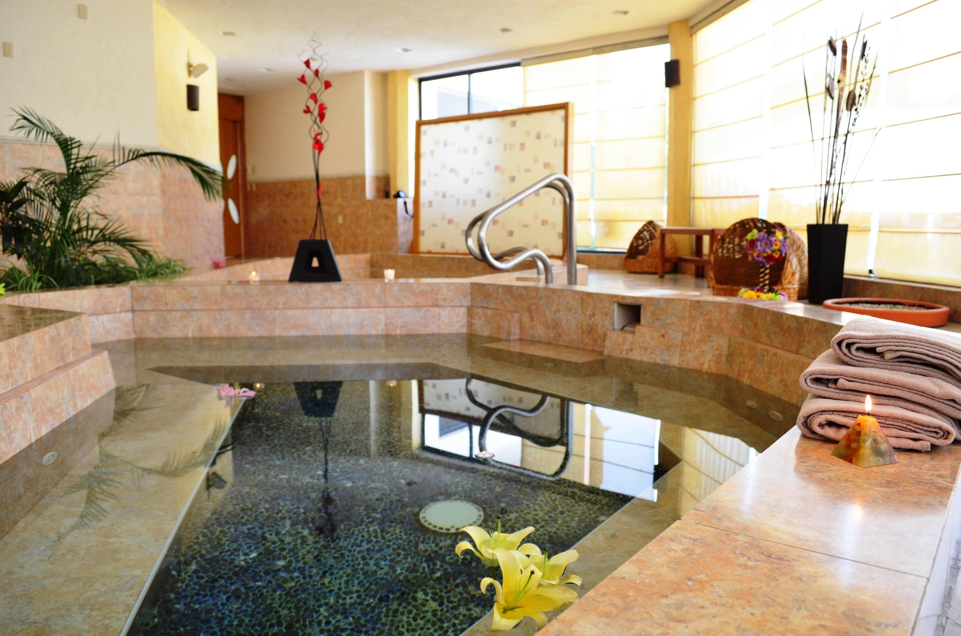 Área de spa com hidromassagem, pia e espelho.
