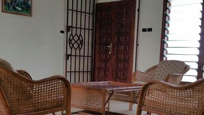 Um quarto com mobiliário de vime, uma porta de madeira e um quadro na parede.