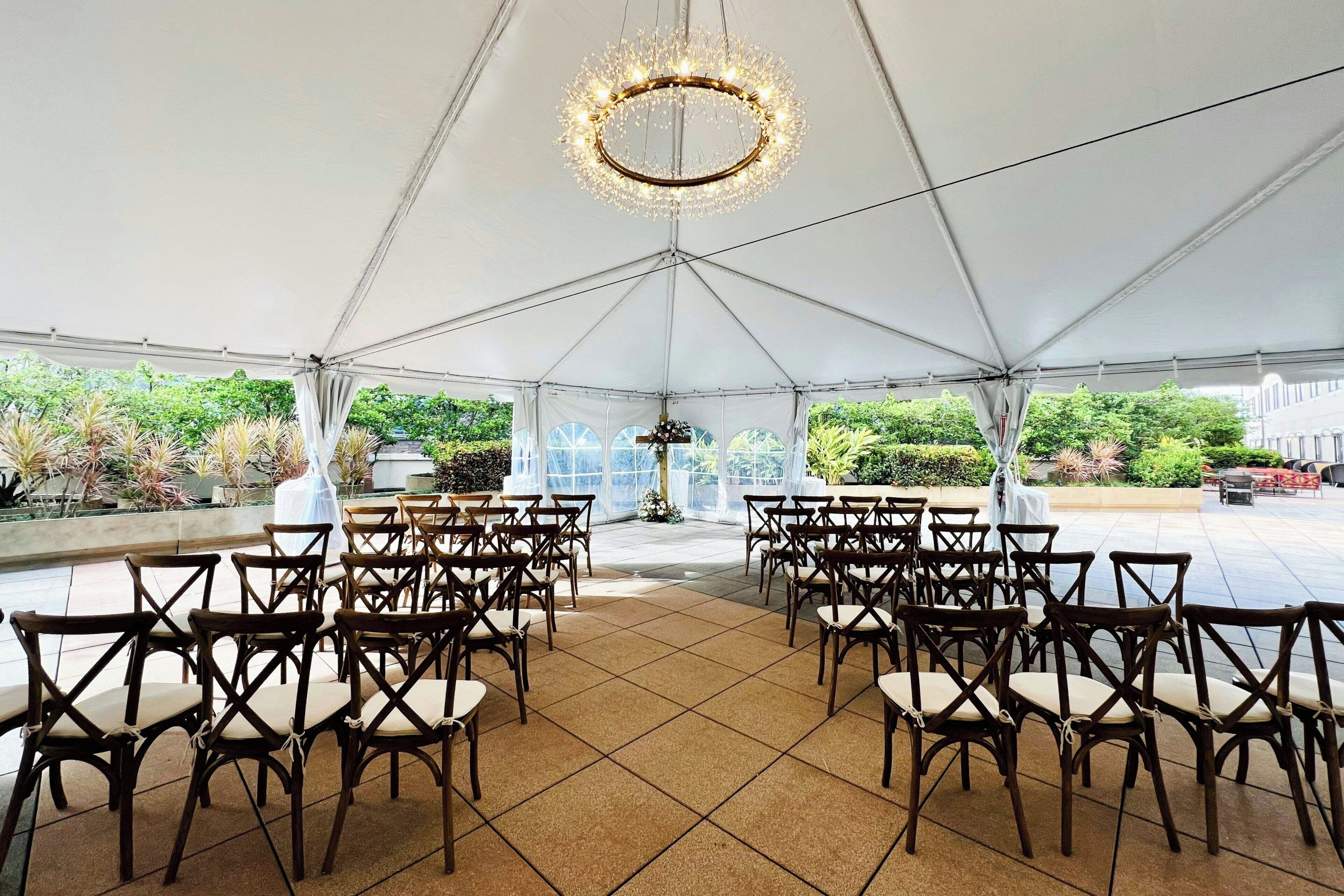 Uma tenda com um candelabro, cadeiras organizadas e vista para o verde lá fora.
