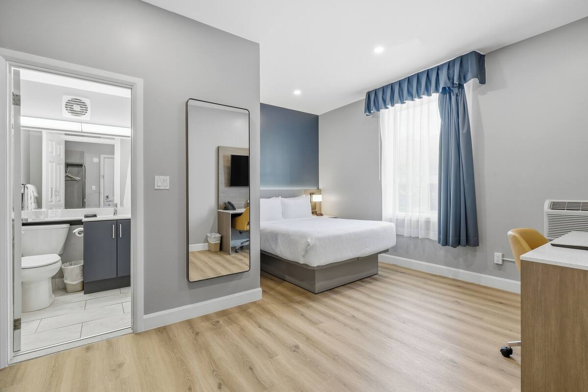 Quarto de hotel moderno com cama, mesa de cabeceira e escrivaninha.