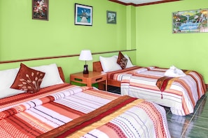 Quarto de hotel com duas camas, uma mesa de cabeceira e uma luminária.