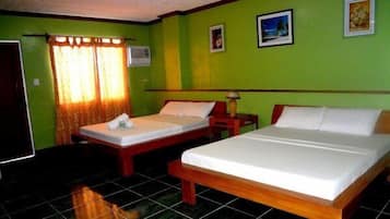 Quarto com duas camas, uma janela com cortinas, ar-condicionado fixado na parede e uma mesinha com abajur.