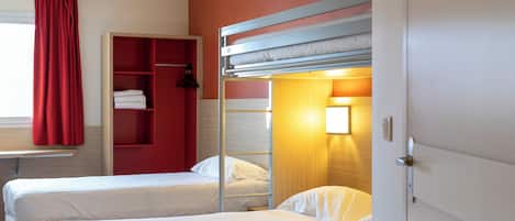 Quarto de hotel com duas camas, um guarda-roupa vermelho e uma janela com cortinas vermelhas.