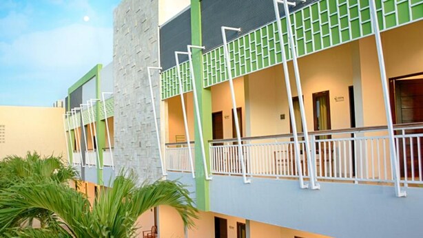 Um hotel com vários andares, varandas, fachada de pedra e céu claro.
