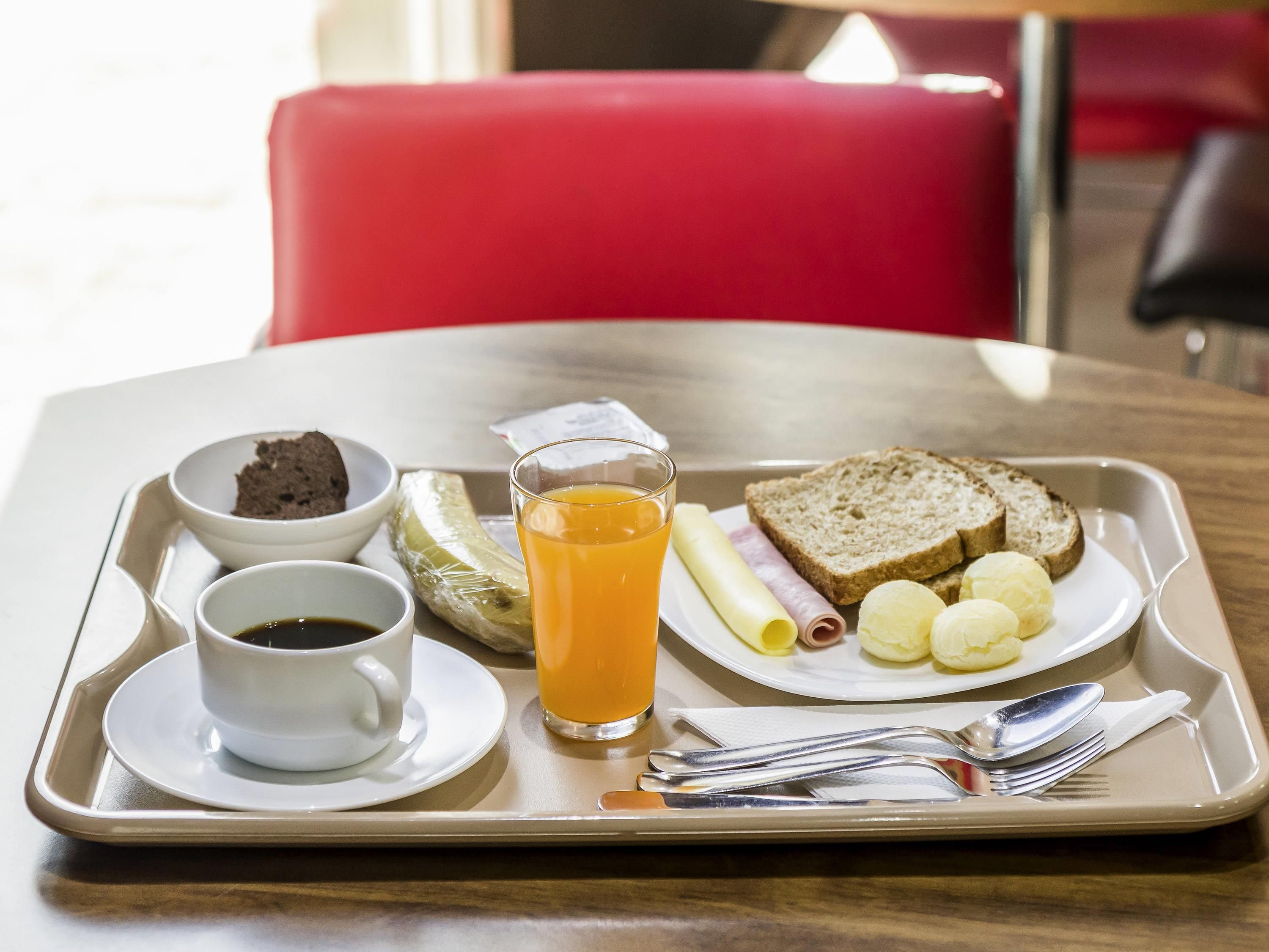Uma bandeja com itens de café da manhã, incluindo torradas, ovos, suco e café.