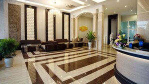 Um lobby moderno com balcão de recepção, área de estar e iluminação decorativa.