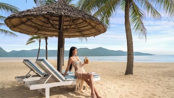 Na praia, praia de areia branca, espreguiçadeiras, guarda-sóis de praia