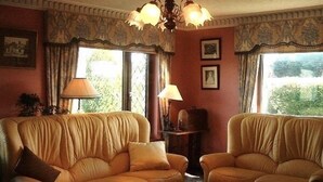 Uma sala de estar acolhedora com dois sofás de couro, um candelabro e quadros nas paredes.