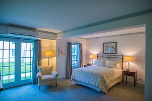 Um quarto com uma cama, duas mesas de cabeceira com luminárias, uma cadeira e uma janela com cortinas.