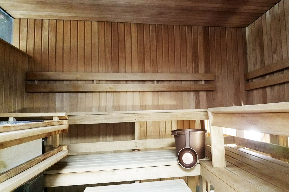 Uma sauna com bancos de madeira e um cesto de lixo.