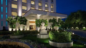 Entrada de hotel com uma estátua, caminhos bem iluminados e jardins bem cuidados.