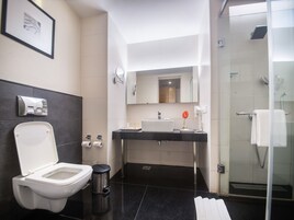 Casa de banho moderna com sanita, lavatório e chuveiro.