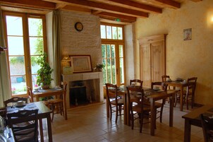 Uma sala de jantar com móveis de madeira, lareira e janelas amplas.