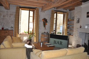 Um quarto aconchegante com teto de madeira, um sofá, uma mesa com placa de bar e uma parede de pedra.