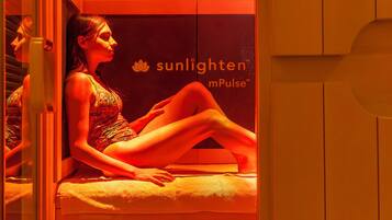 Uma sauna com uma mulher sentada no interior, um logotipo na parede e painéis de madeira.