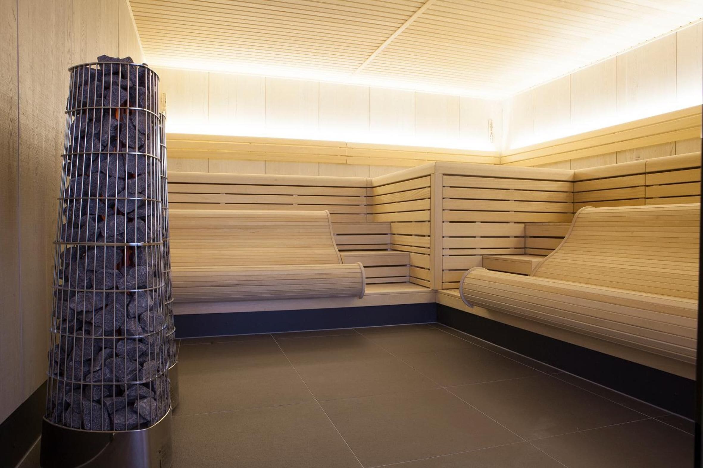 Uma sala de sauna com bancos de madeira e um recipiente de metal para pedras.