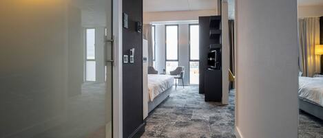 Corredor de hotel com uma cama, uma TV e uma escrivaninha.