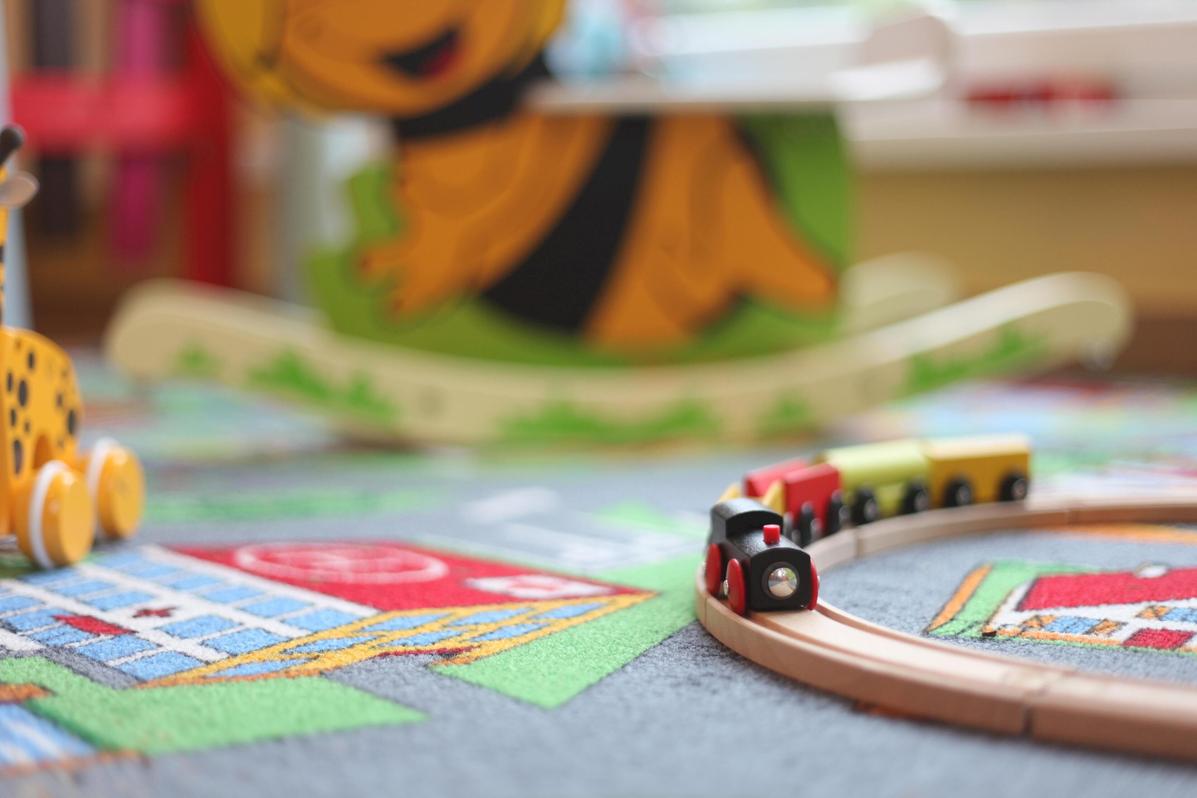 Um conjunto de trens de brinquedo sobre um tapete de jogo colorido.