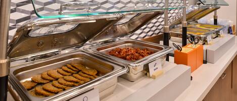 Buffet com bandejas identificadas de salsicha de peru, bacon e outros alimentos.