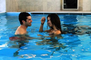 Uma piscina com água azul cristalina e borda revestida de azulejos.