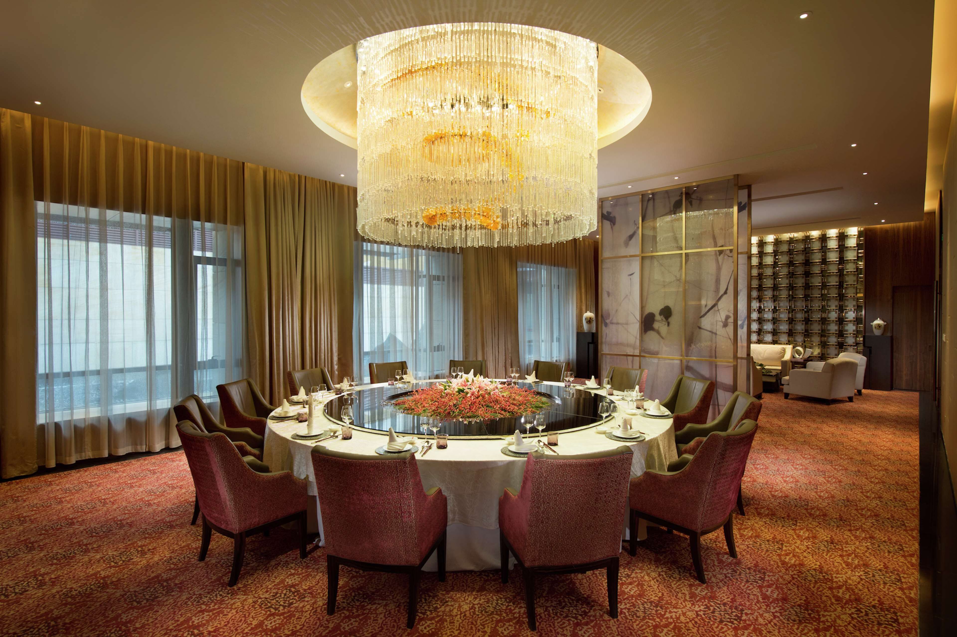Uma mesa redonda com cadeiras, um candelabro e um arranjo floral.