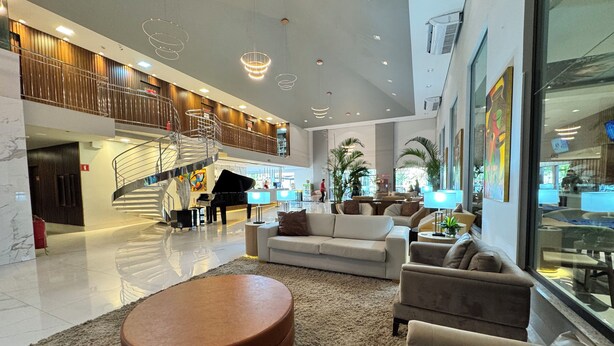 Um hall espaçoso com um piano de cauda, assentos confortáveis, uma escadaria e vista da área do hall.